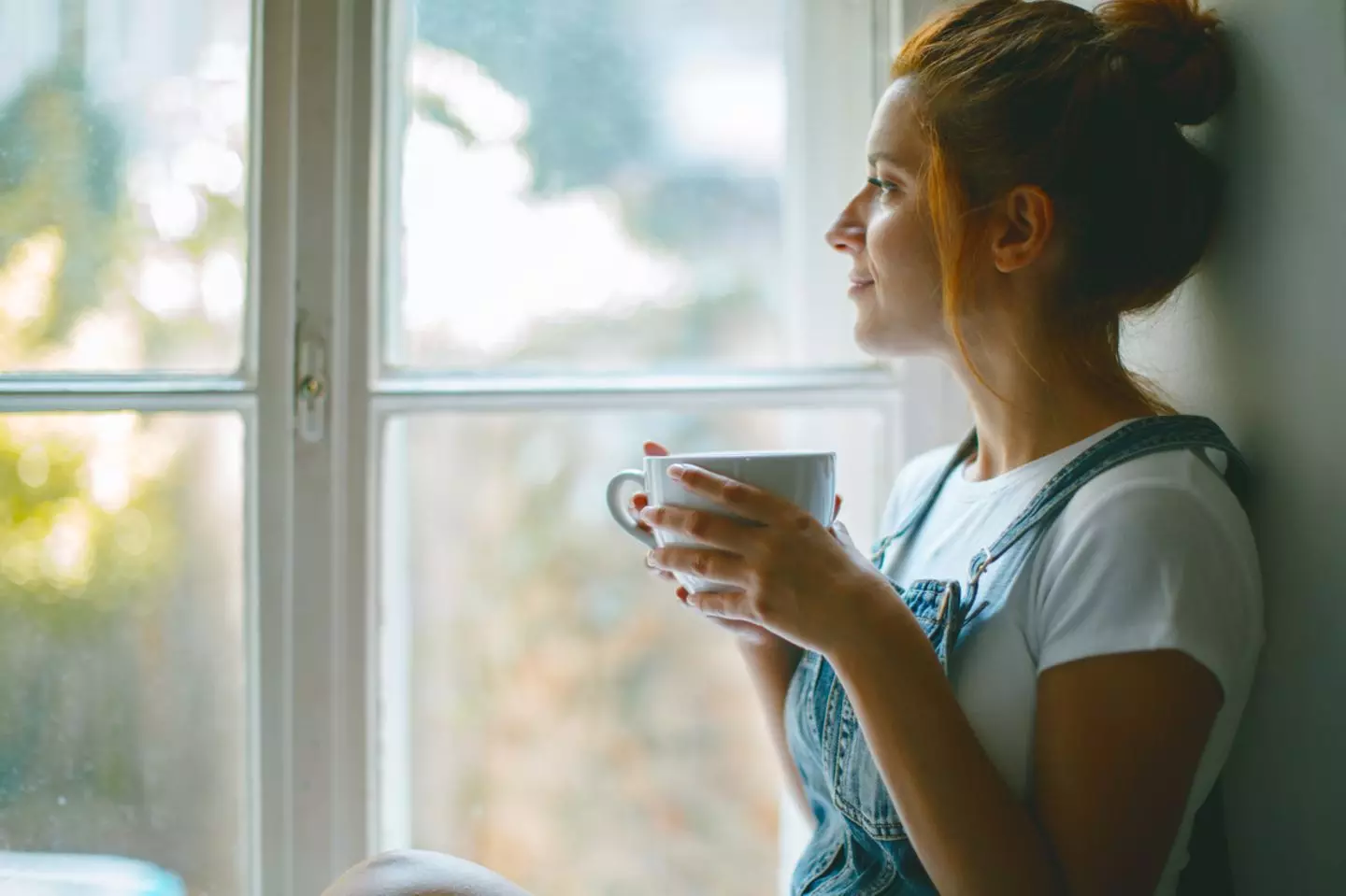 Young woman drinking coffee by the window