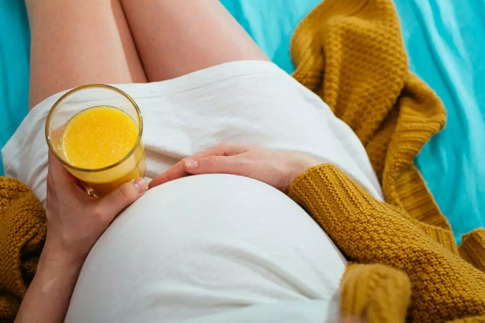 Pregnant woman drinks a glass of orange juice