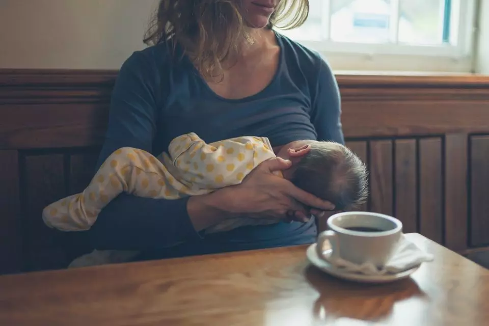 Mother breastfeeds baby in cafe